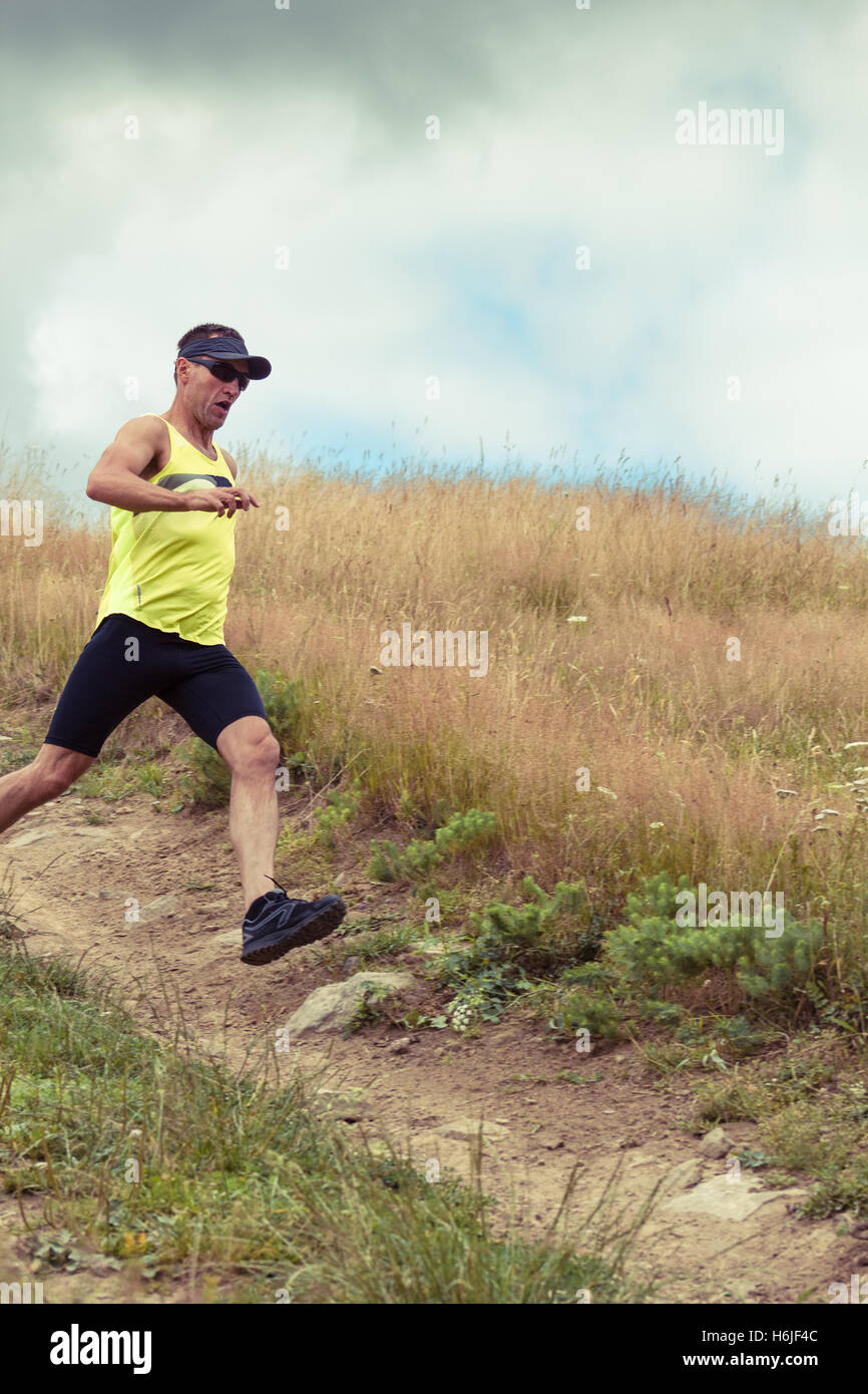 Athlete male runner running downhill on dirt road and jumping Stock ...