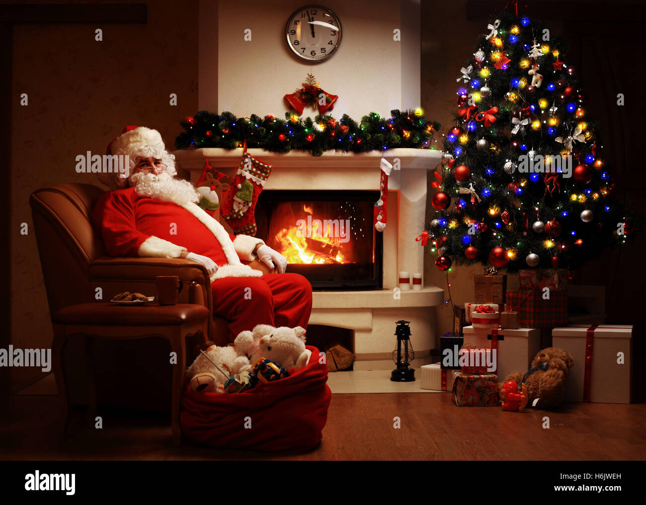 Santa Claus having a rest in a comfortable chair near the fireplace at ...