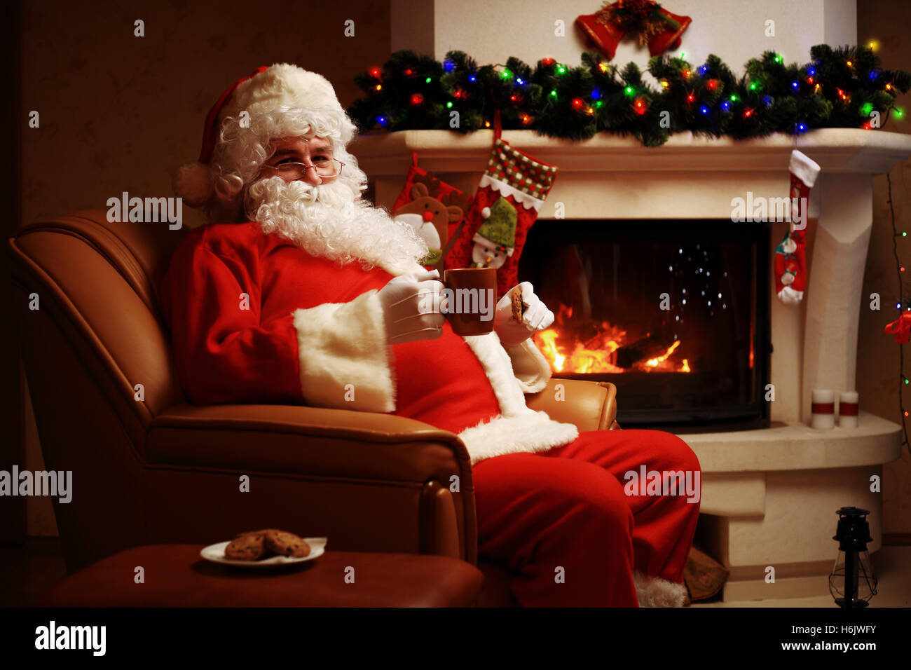 Santa Claus having a rest in a comfortable chair near the fireplace at ...
