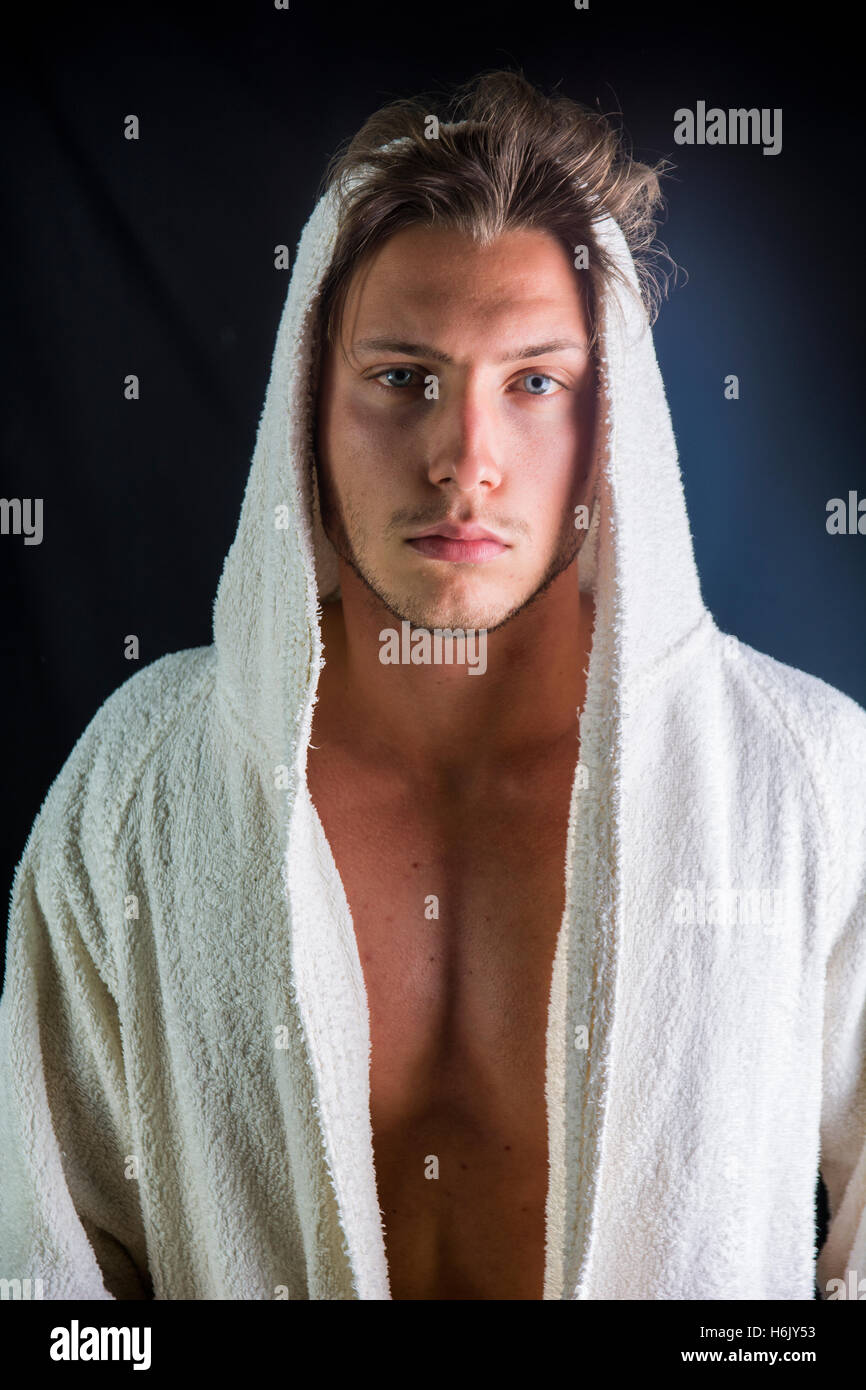 Handsome young man wearing white bathrobe, on dark background Stock ...