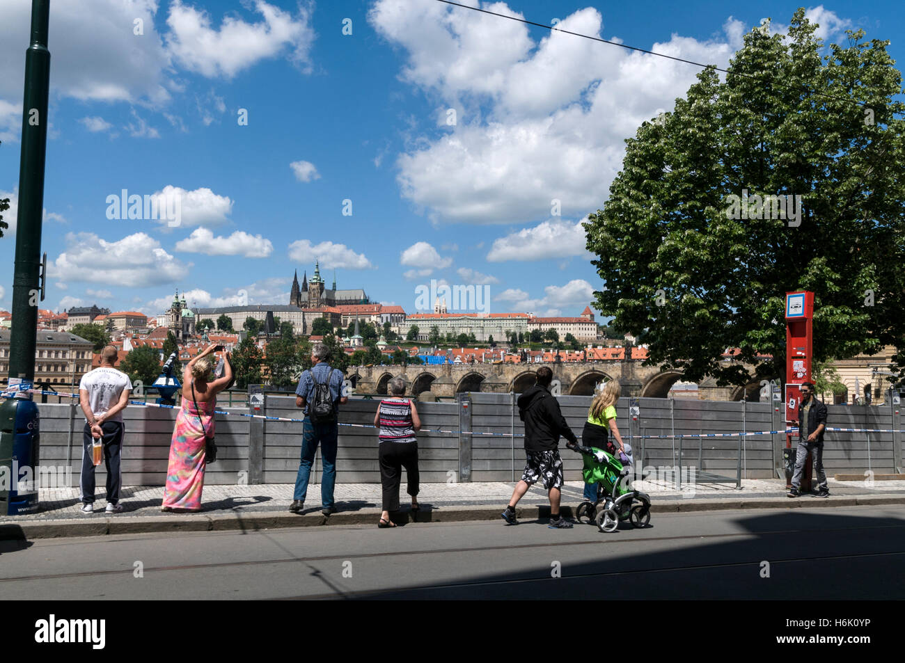 Crowds gather behind temporary fenced-off flood barriers along the ...
