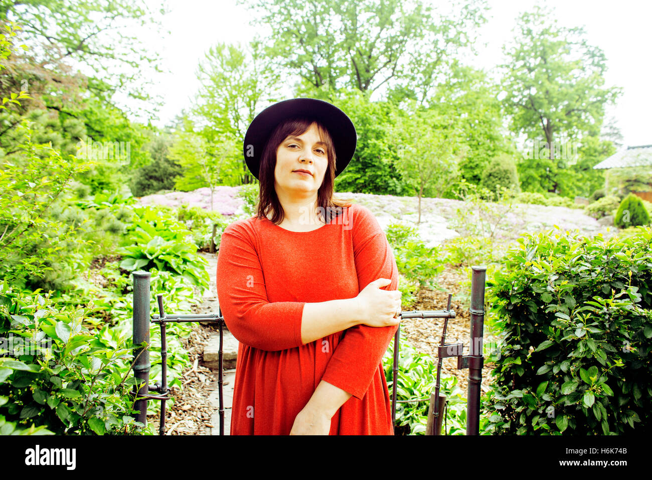 mature brunette woman in green garden wearing hat, smiling, frie Stock ...