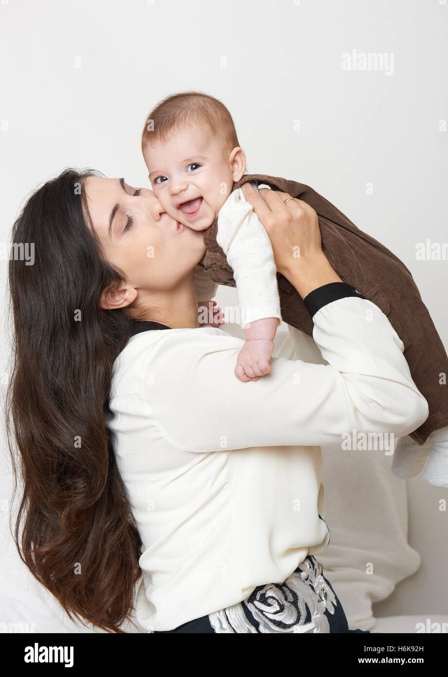 Mother raising baby and play, happy family portrait on white background ...
