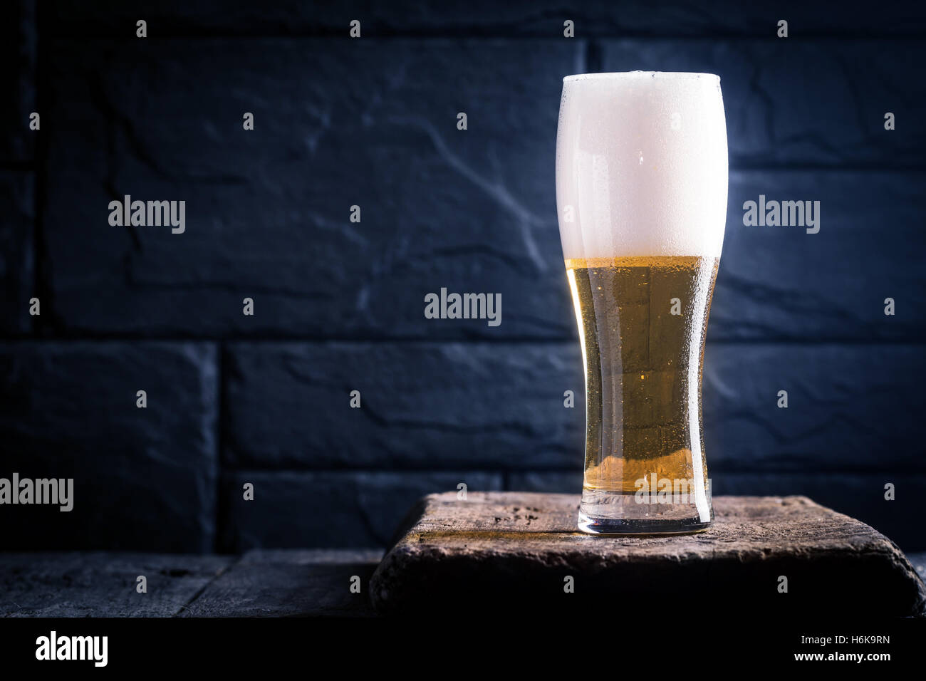 Glass of light beer with bubbles near black wall Stock Photo - Alamy