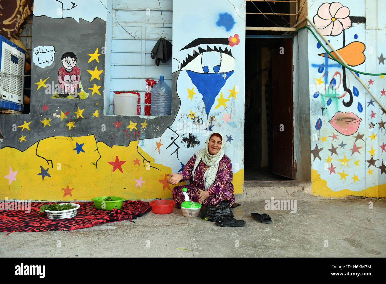 Aqrah, Iraq. 19th Oct, 2016. A woman prepares food outside the painted ...