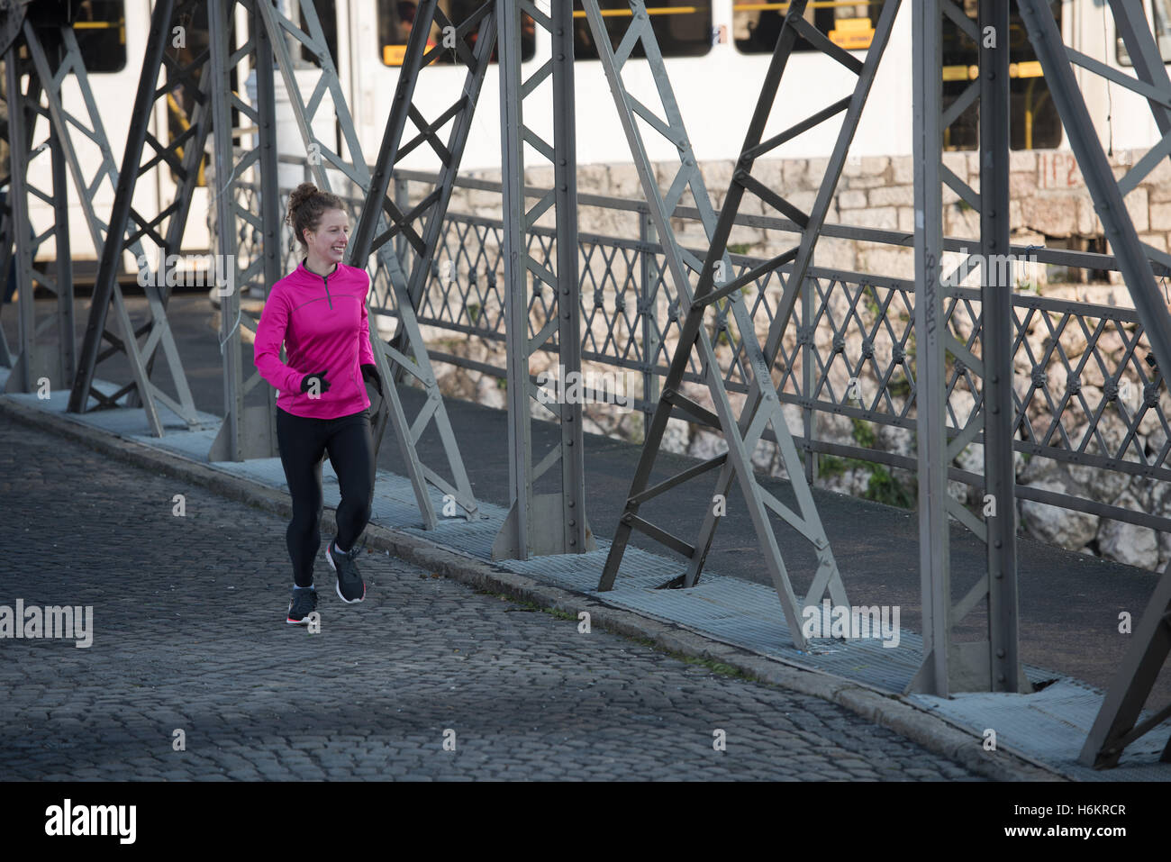 sporty woman running on sidewalk at early morning jogging with city ...