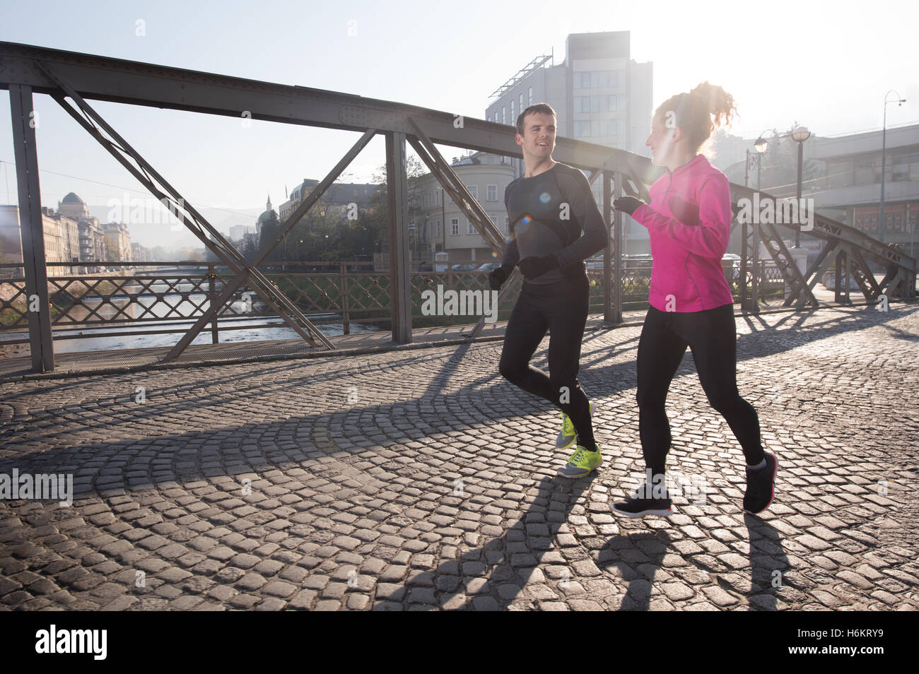 healthy young couple jogging in the city at early morning with sunrise ...