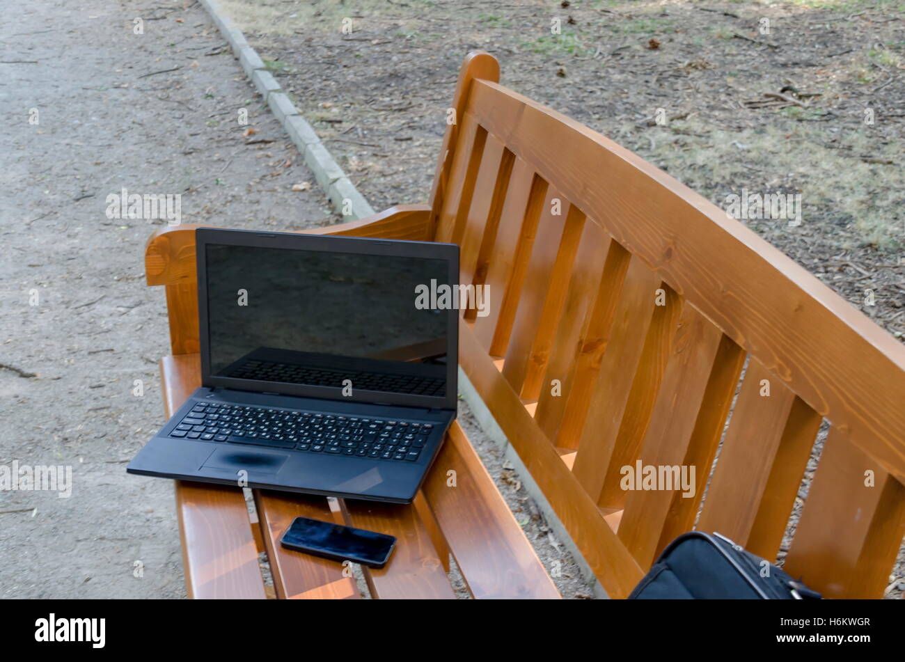 Open laptop computer, bag and phone on wooden bench in the park, Sofia ...
