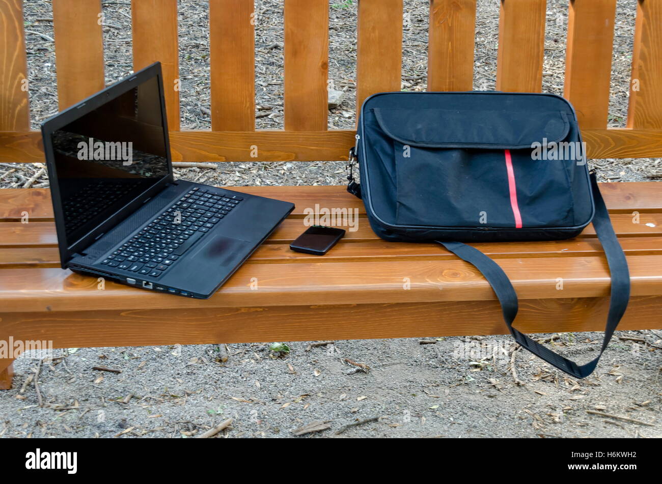 Open laptop computer, bag and phone on wooden bench in the park, Sofia ...