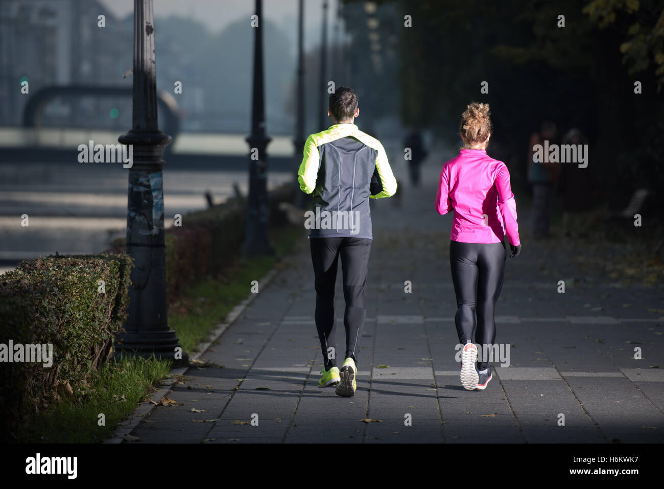 healthy young couple jogging in the city at early morning with sunrise ...