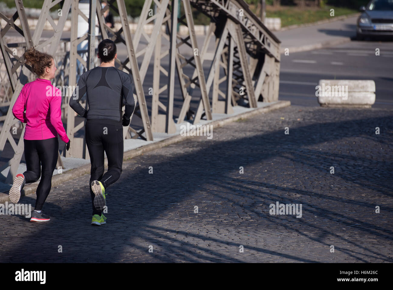 healthy young couple jogging in the city at early morning with sunrise ...