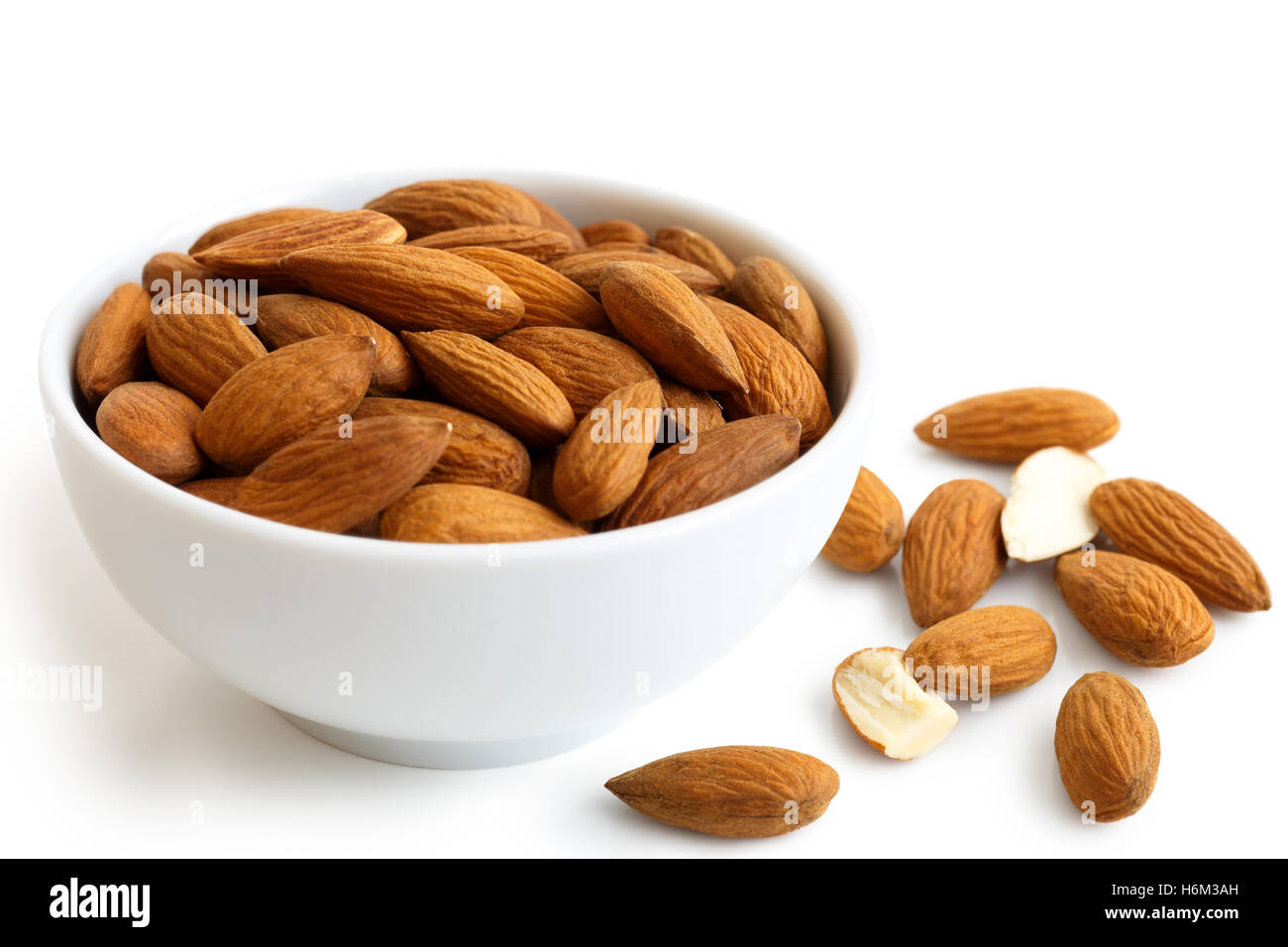 White bowl of whole almonds on white. Spilled almonds Stock Photo - Alamy