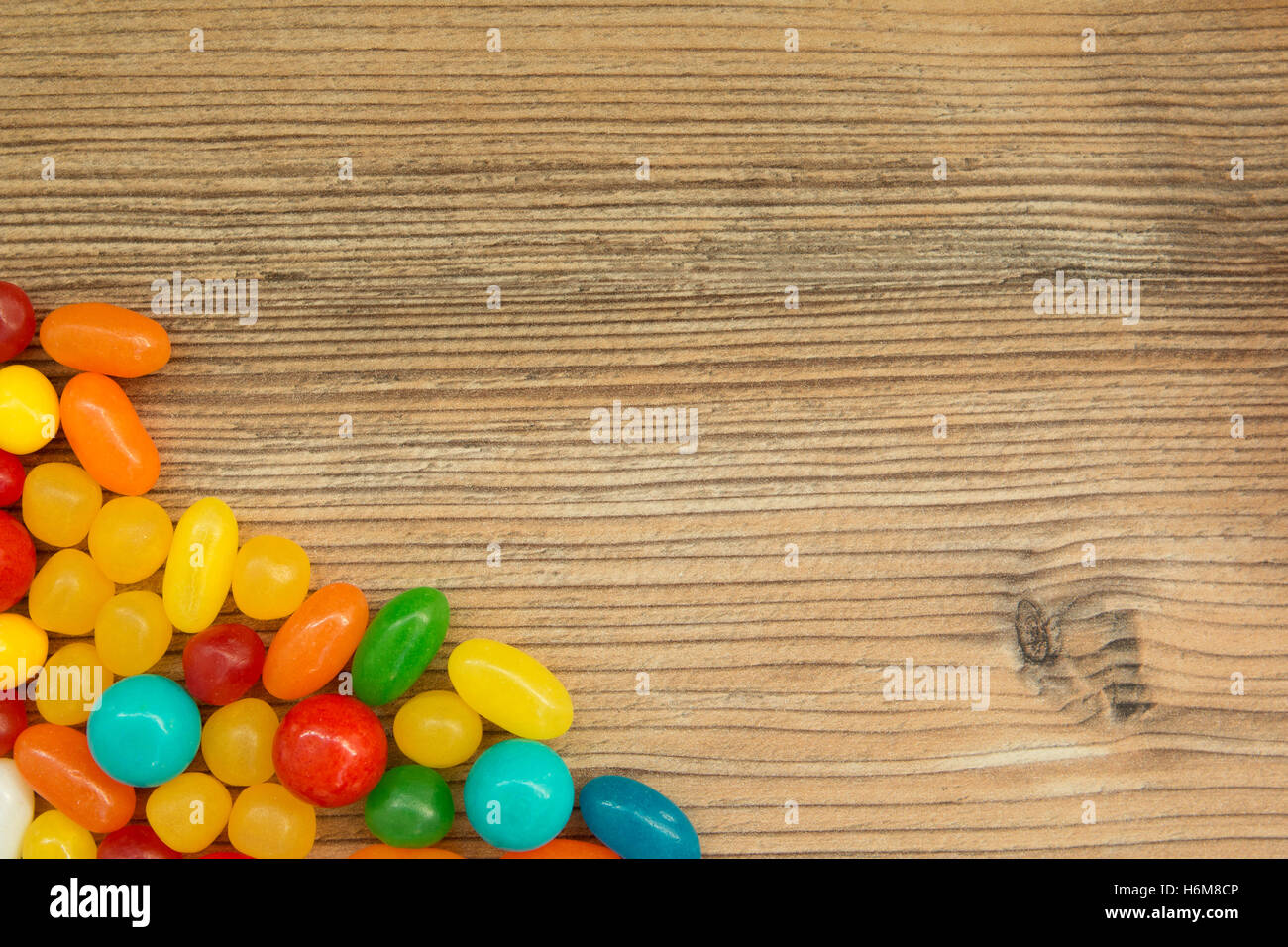 Colorful jelly beans shaped a frame to write your text on a wooden ...