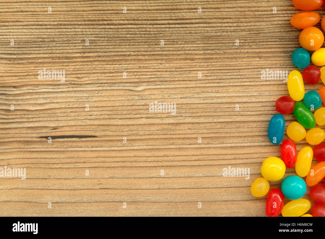Colorful jelly beans shaped a frame to write your text on a wooden ...