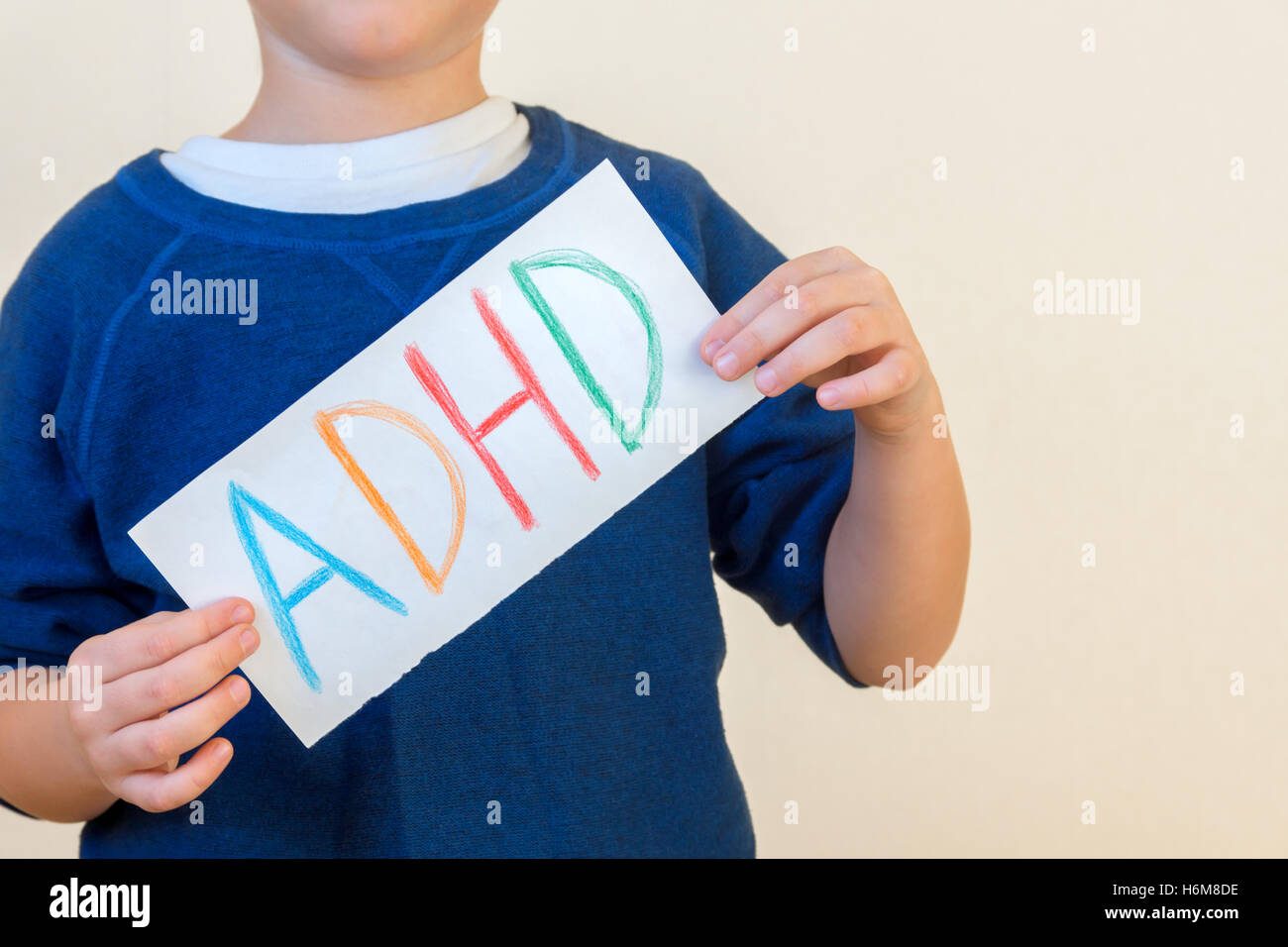Young boy holds ADHD text written on sheet of paper. ADHD is Attention ...