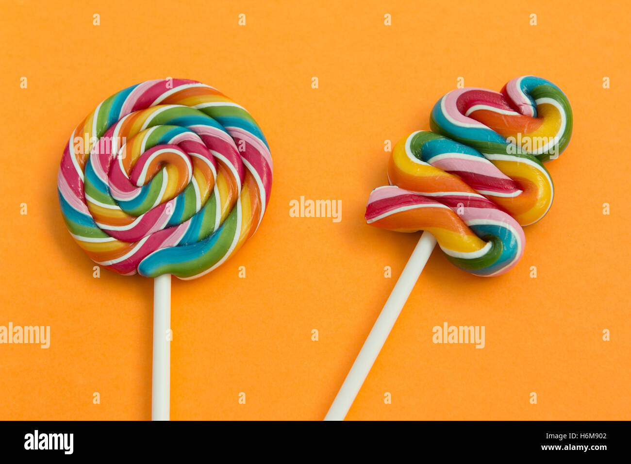 Two lollipops with many colors in a spiral on a orange background Stock ...