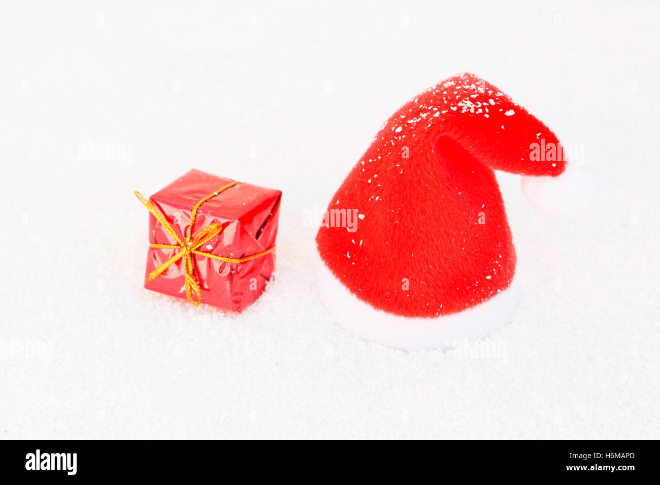 Santa hat on snow with one gift. Christmas in red Stock Photo - Alamy