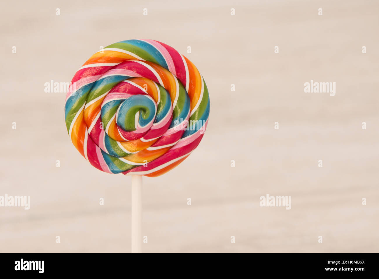 Nice round lollipop with many colors in a spiral on a wooden background ...