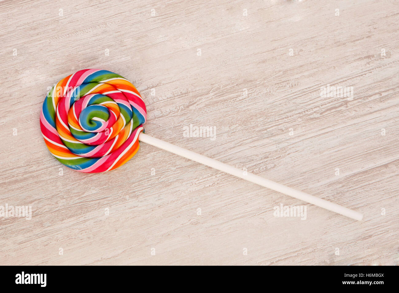 Nice round lollipop with many colors in a spiral on a wooden background ...