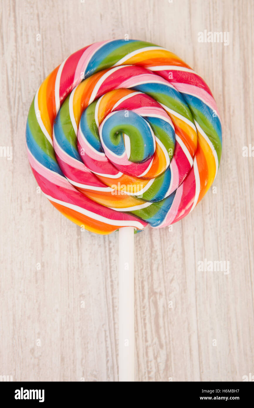 Nice round lollipop with many colors in a spiral on a wooden background ...