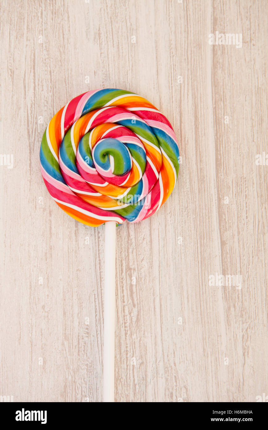 Nice round lollipop with many colors in a spiral on a wooden background ...