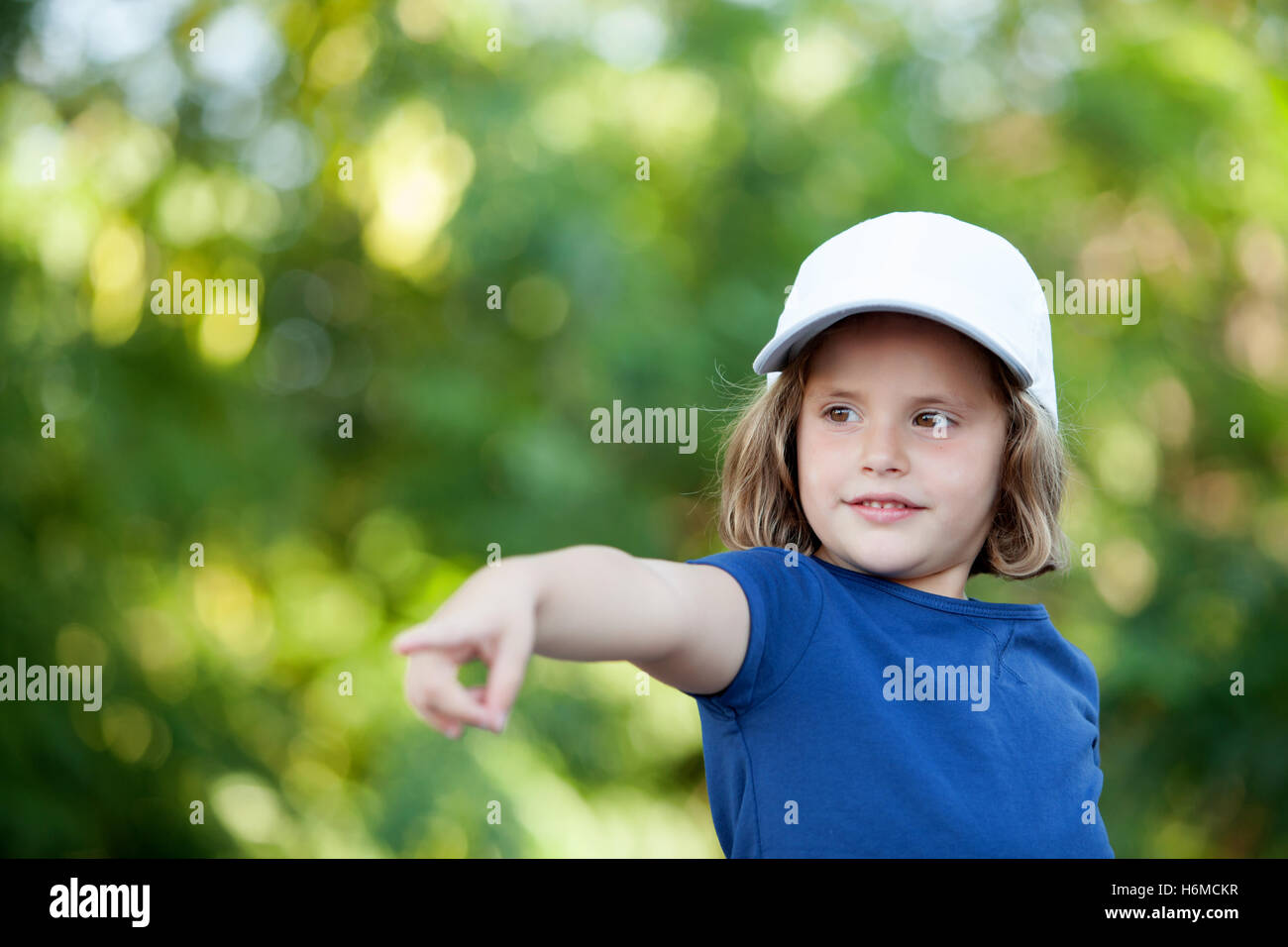 Little cute girl with a cap in the park indicating the direction Stock ...