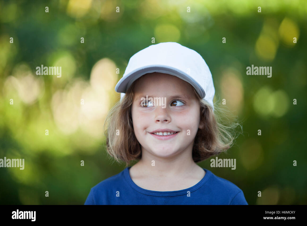 Little cute girl with a cap in the park happy Stock Photo - Alamy