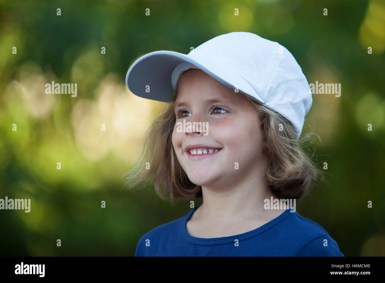 Little cute girl with a cap in the park happy Stock Photo - Alamy