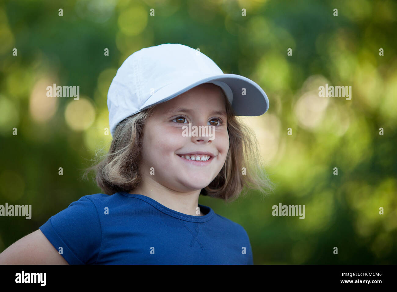 Little cute girl with a cap in the park happy Stock Photo - Alamy