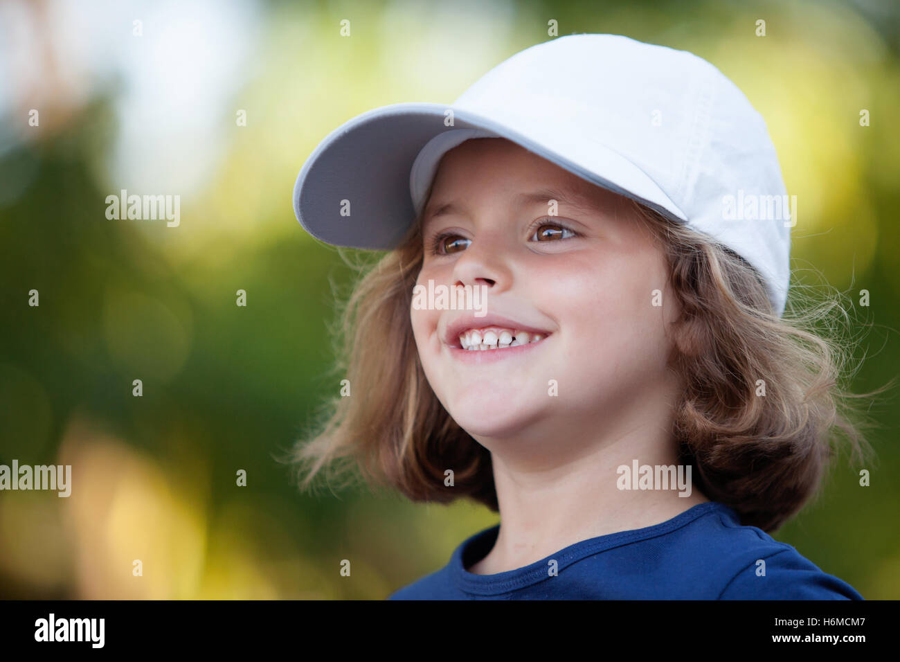 Little cute girl with a cap in the park happy Stock Photo - Alamy