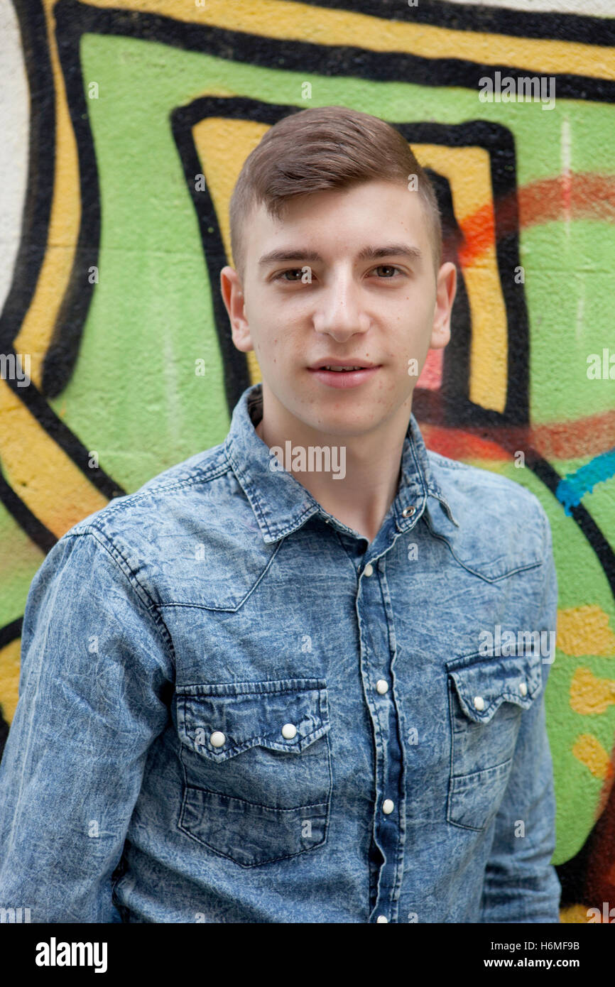 Portrait of a teenager rebellious man on a wall with graffiti ...