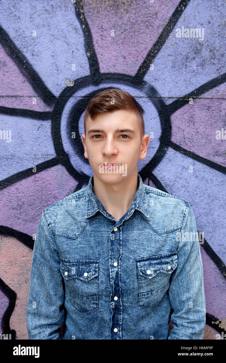 Portrait of a teenager rebellious man on a wall with graffiti ...