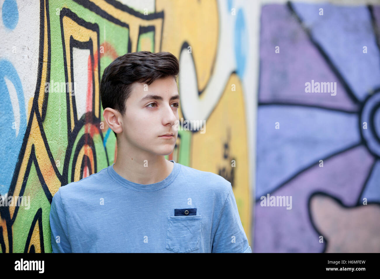 Portrait of a teenager rebellious man on a wall with graffiti ...