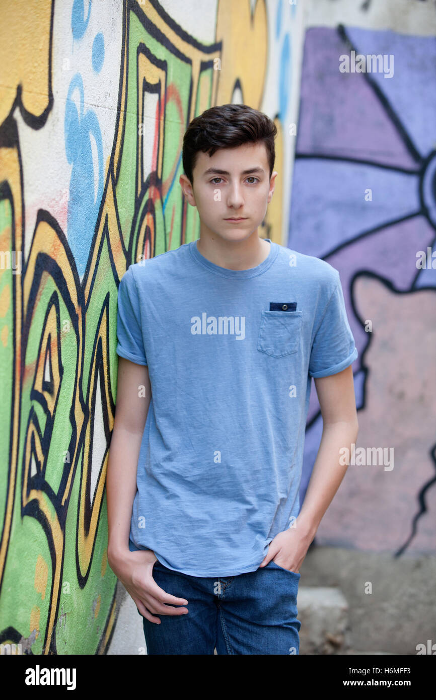Portrait of a teenager rebellious man on a wall with graffiti ...