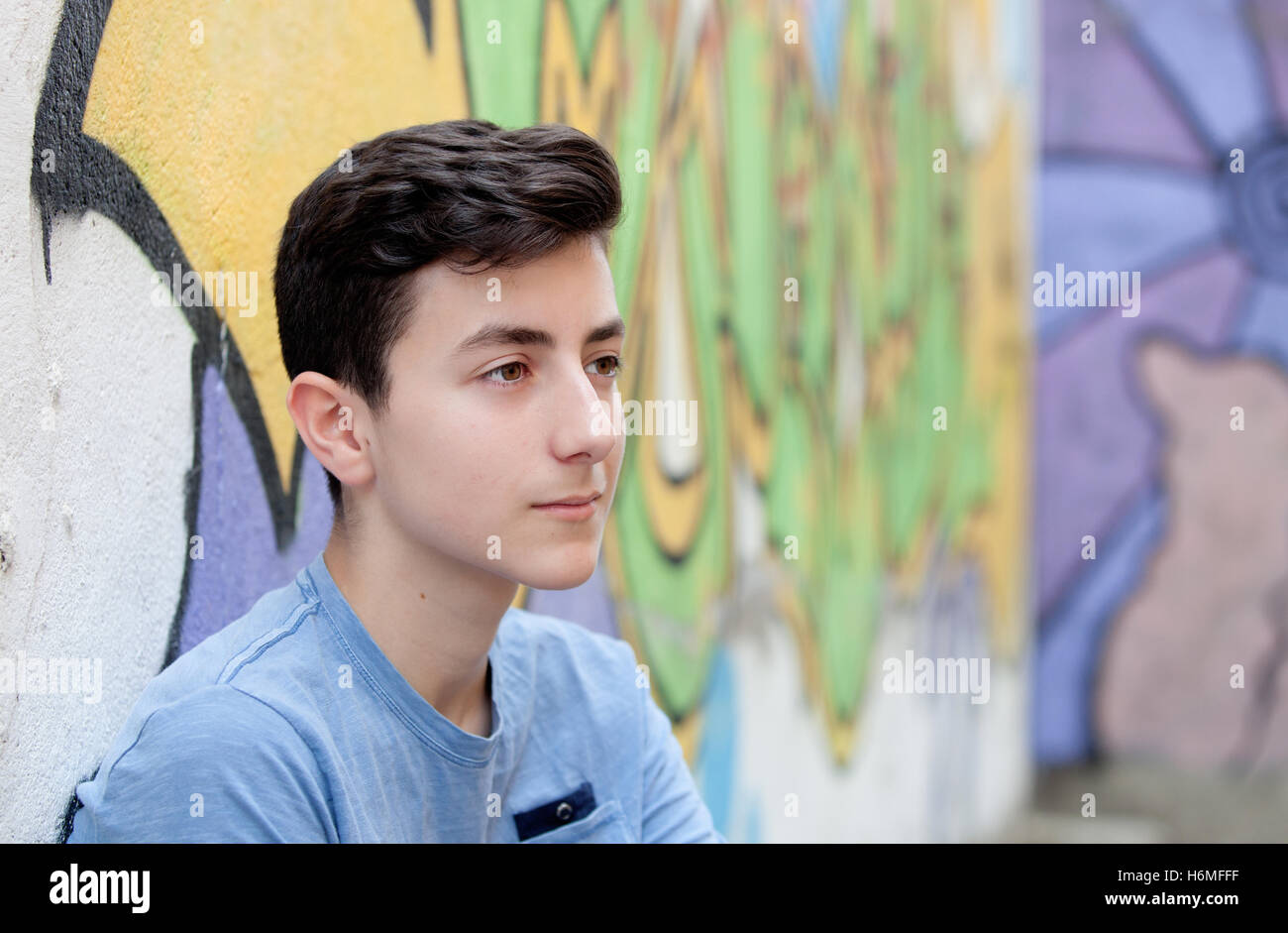 Portrait of a teenager rebellious man on a wall with graffiti ...
