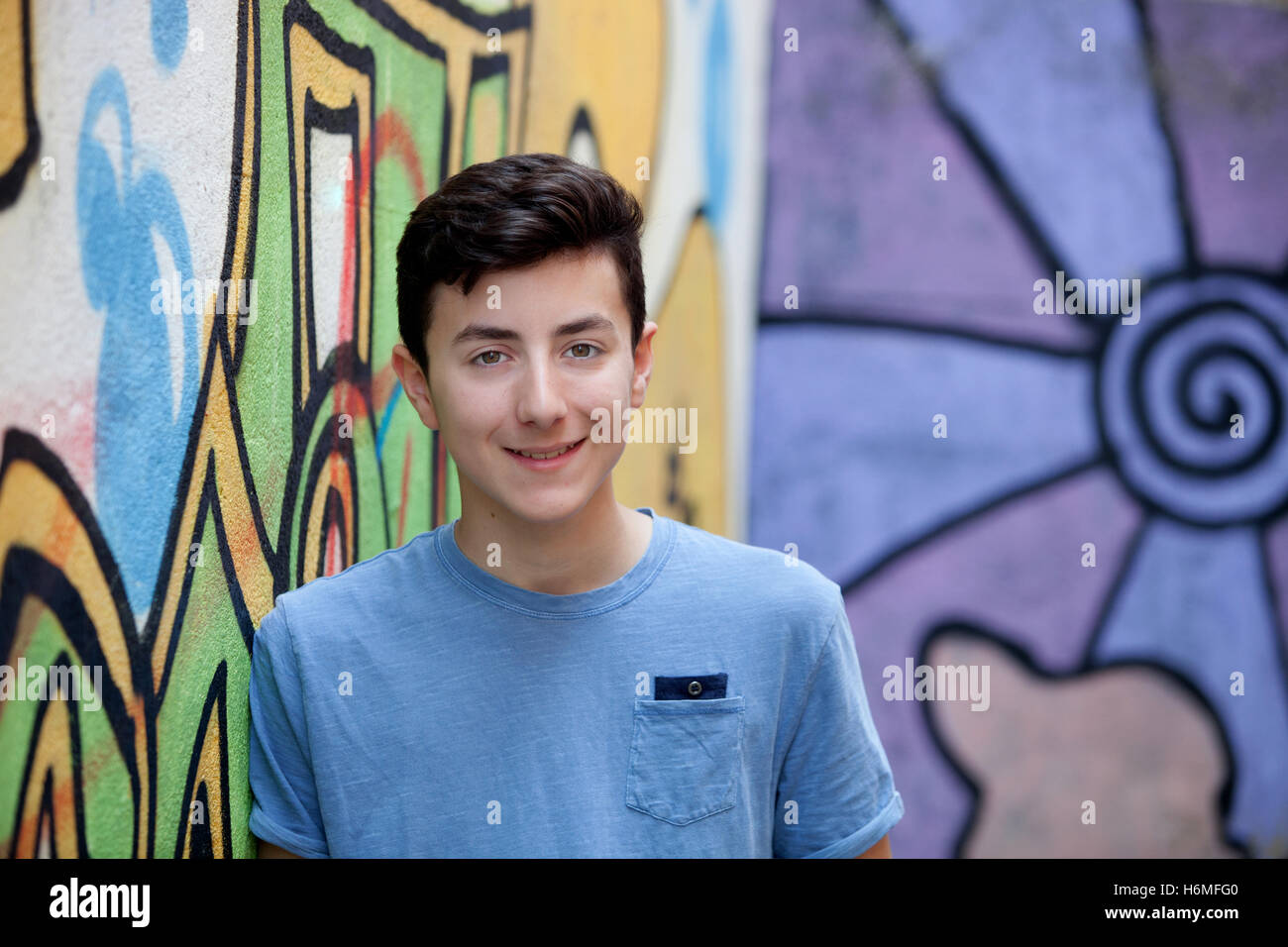 Portrait of a teenager rebellious man on a wall with graffiti ...
