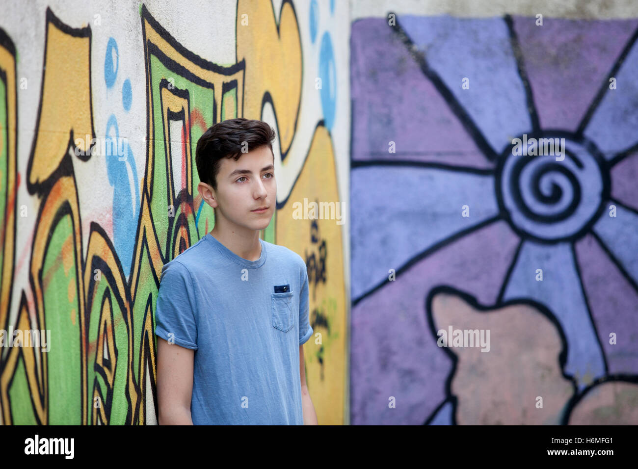 Portrait of a teenager rebellious man on a wall with graffiti ...