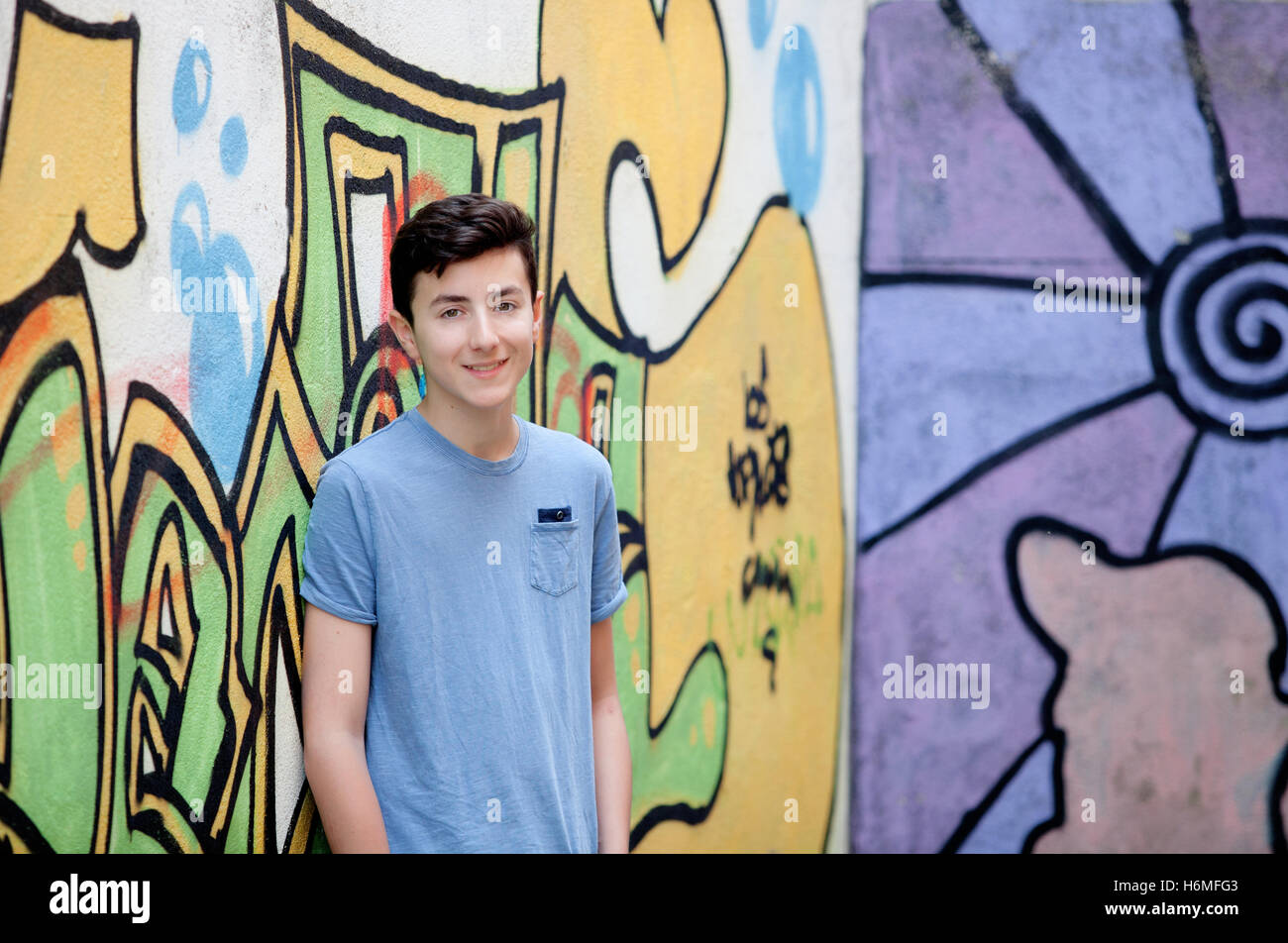Portrait of a teenager rebellious man on a wall with graffiti ...