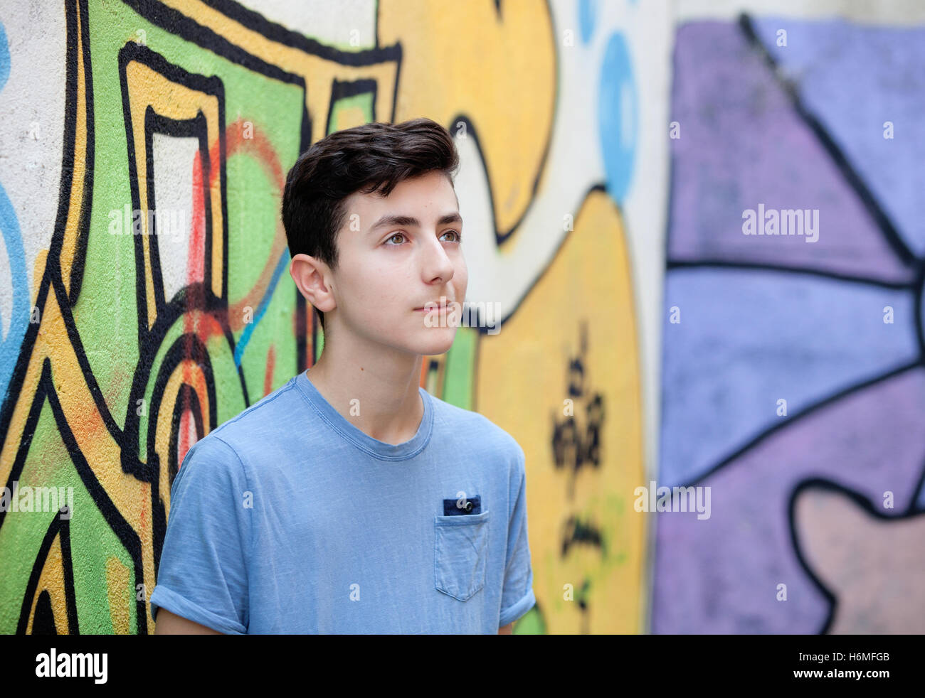 Portrait of a teenager rebellious man on a wall with graffiti ...