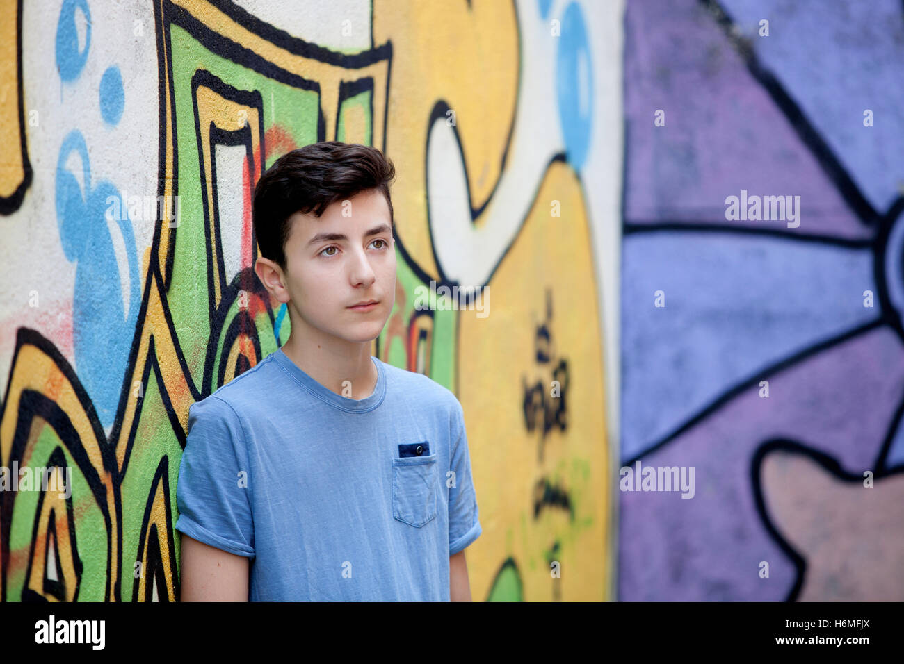 Portrait of a teenager rebellious man on a wall with graffiti ...