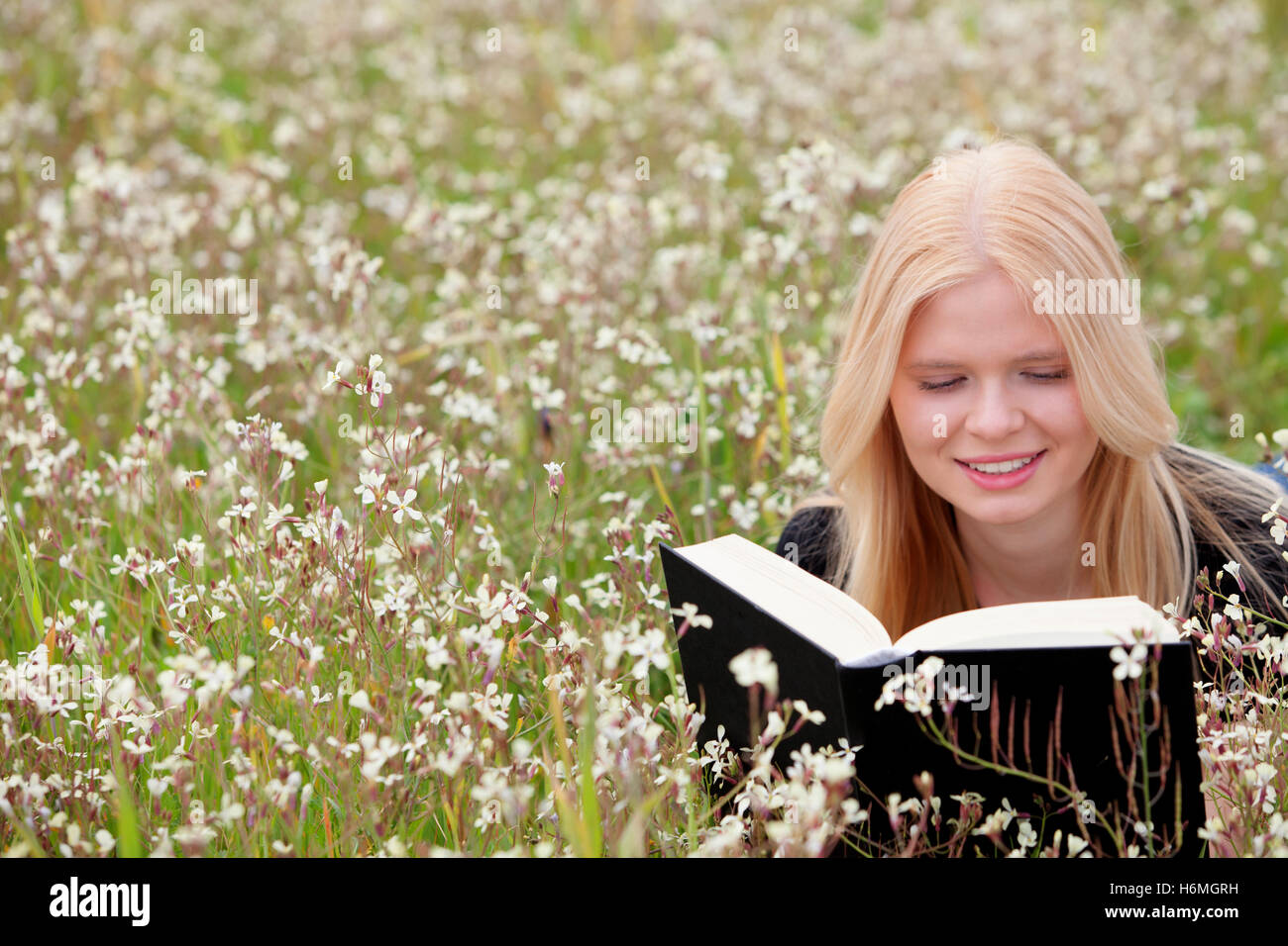 Relaxed young woman reading a book on nature Stock Photo - Alamy