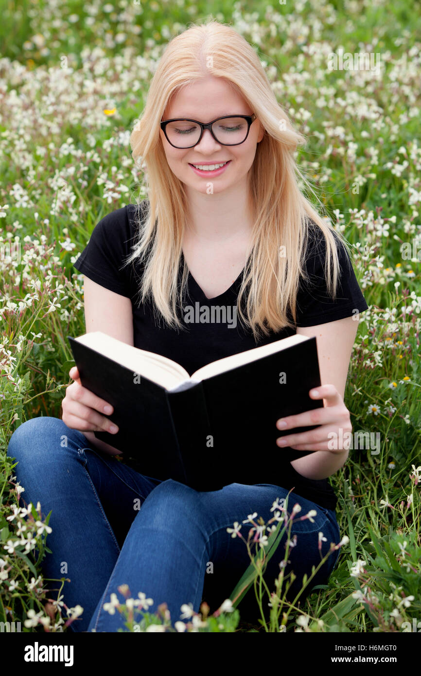 Relaxed young woman reading a book on nature Stock Photo - Alamy