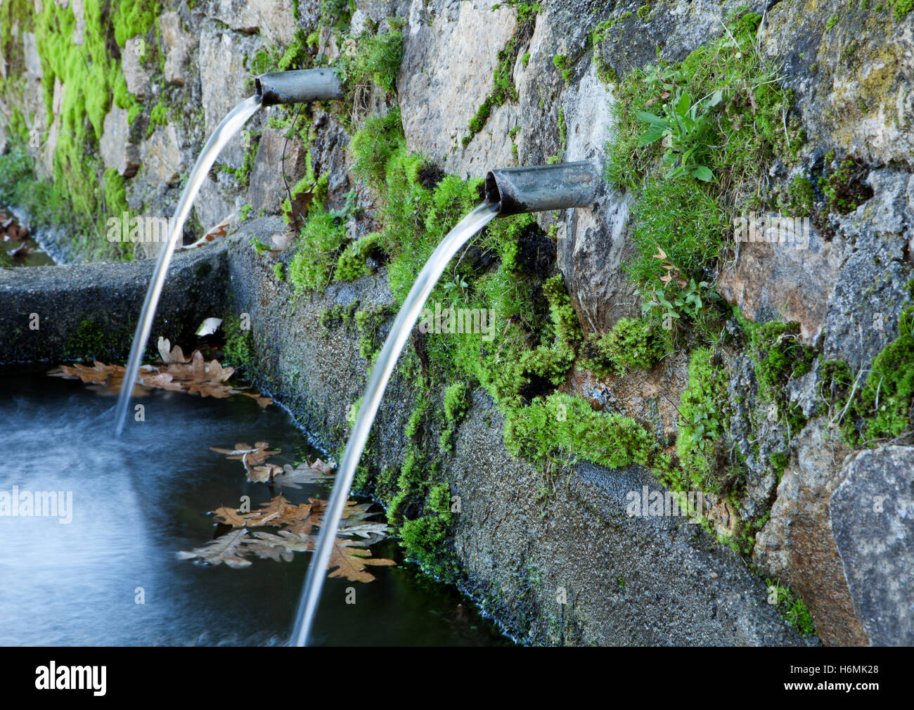 Pipes clean water pouring from a natural source Stock Photo - Alamy