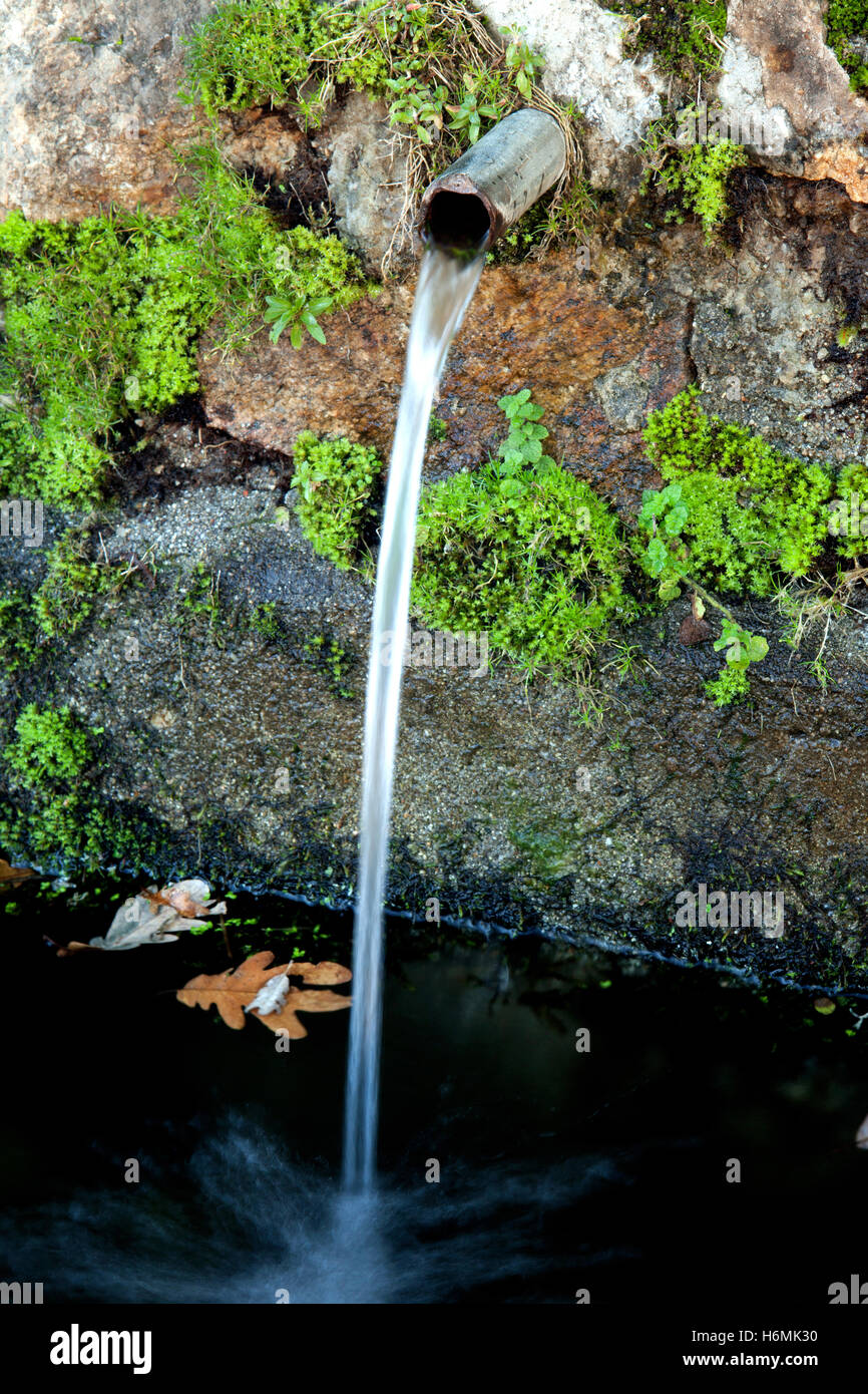 Pipe clean water pouring from a natural source Stock Photo - Alamy