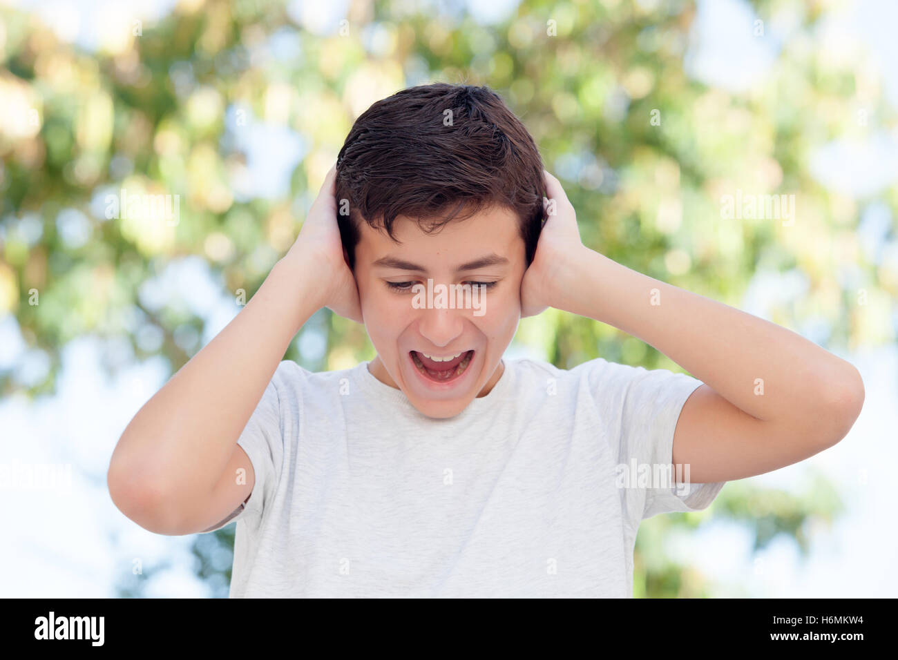 Sad teenager boy outdoor covering his ears Stock Photo - Alamy