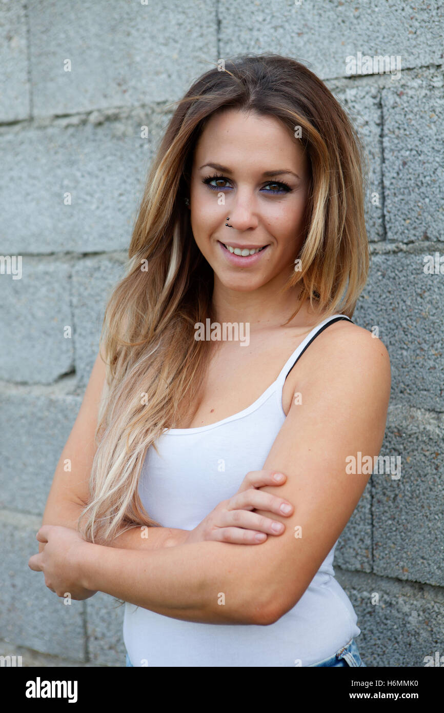 Cool young woman leaning against a gray wall Stock Photo - Alamy