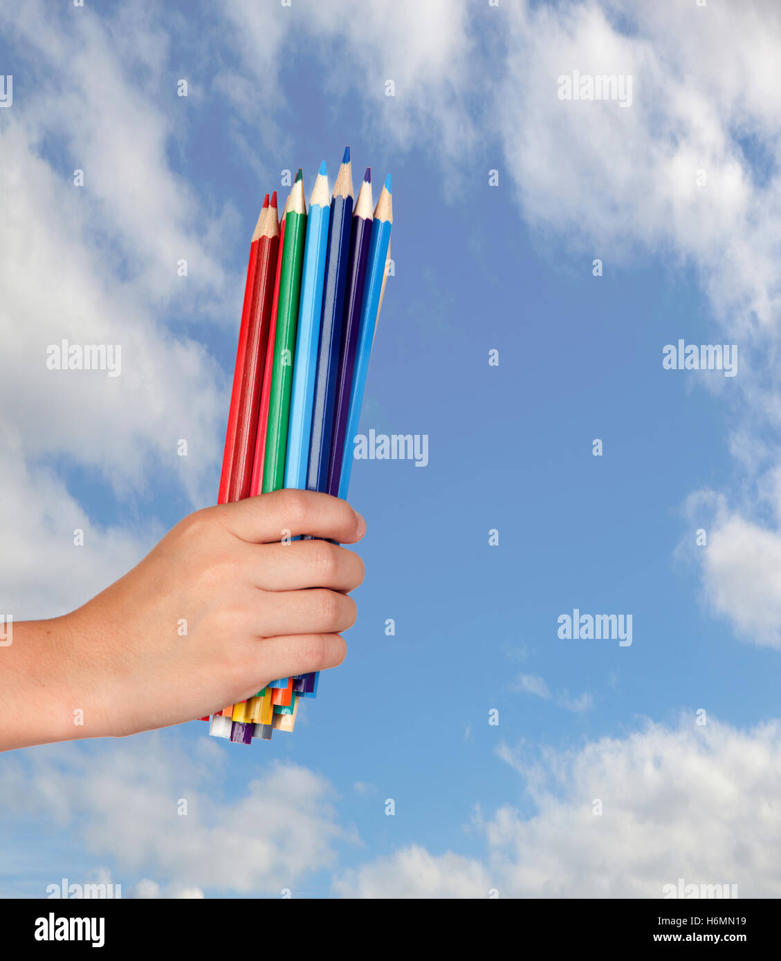 Hand holding many crayons with a blue sky of background Stock Photo - Alamy