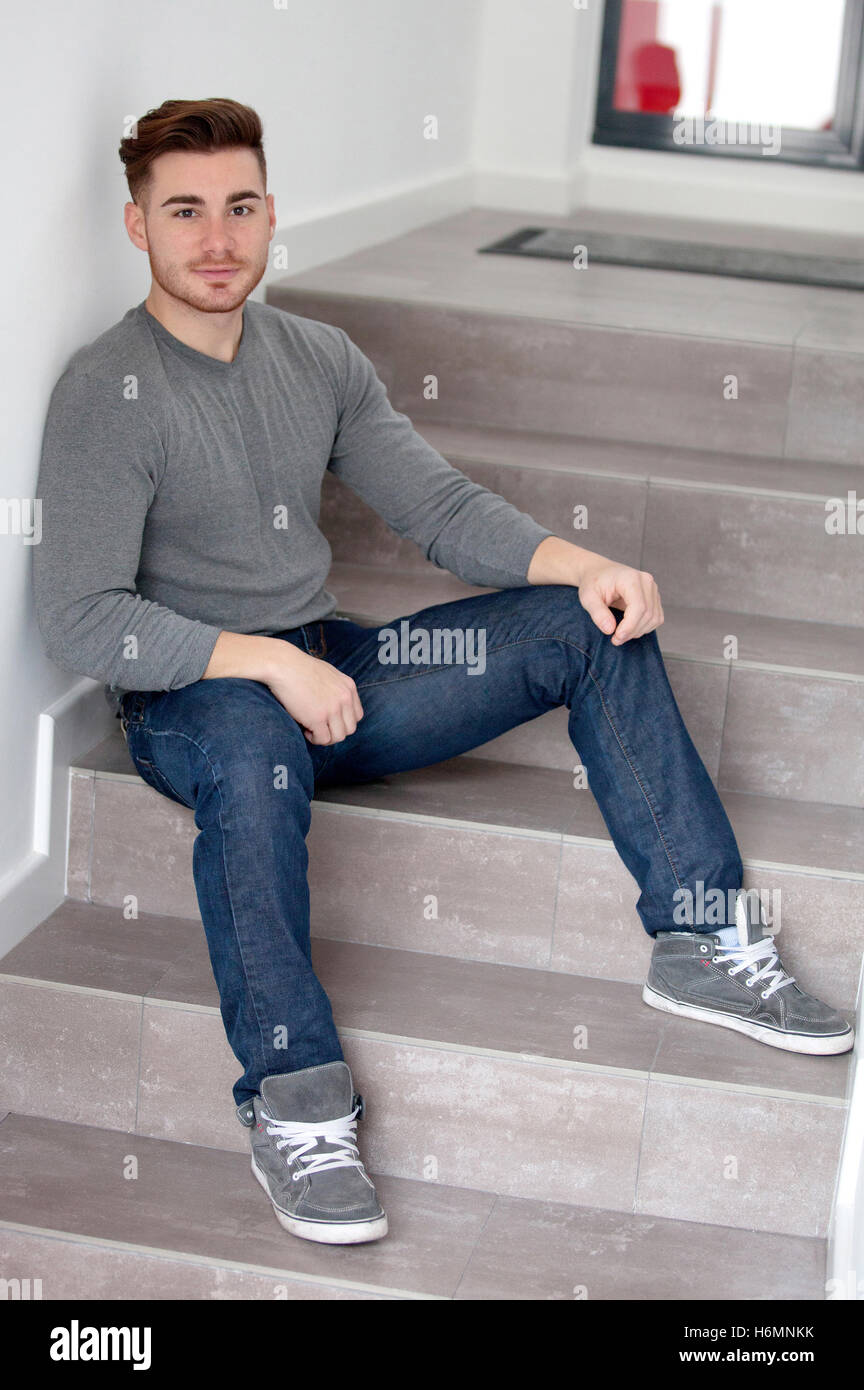 Casual cool man sitting on the stairs at home Stock Photo - Alamy