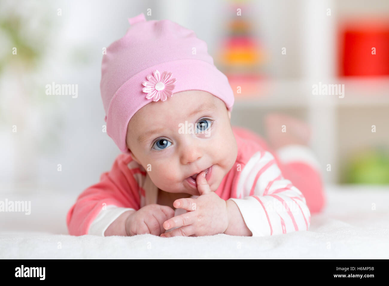smiling cute baby lying on her tummy in nursery Stock Photo - Alamy