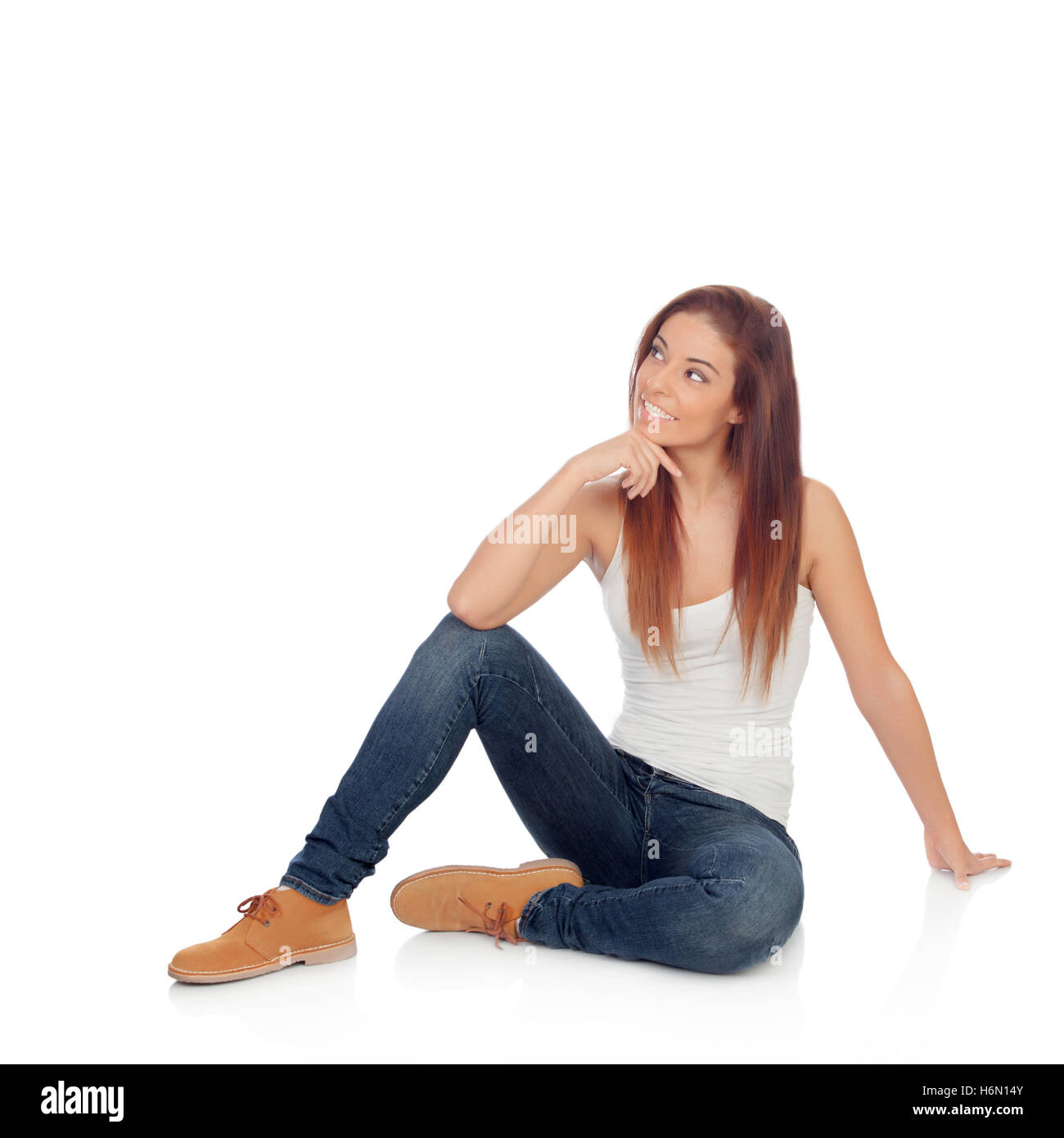 Pensive casual young woman sitting on the floor isolated on a white ...